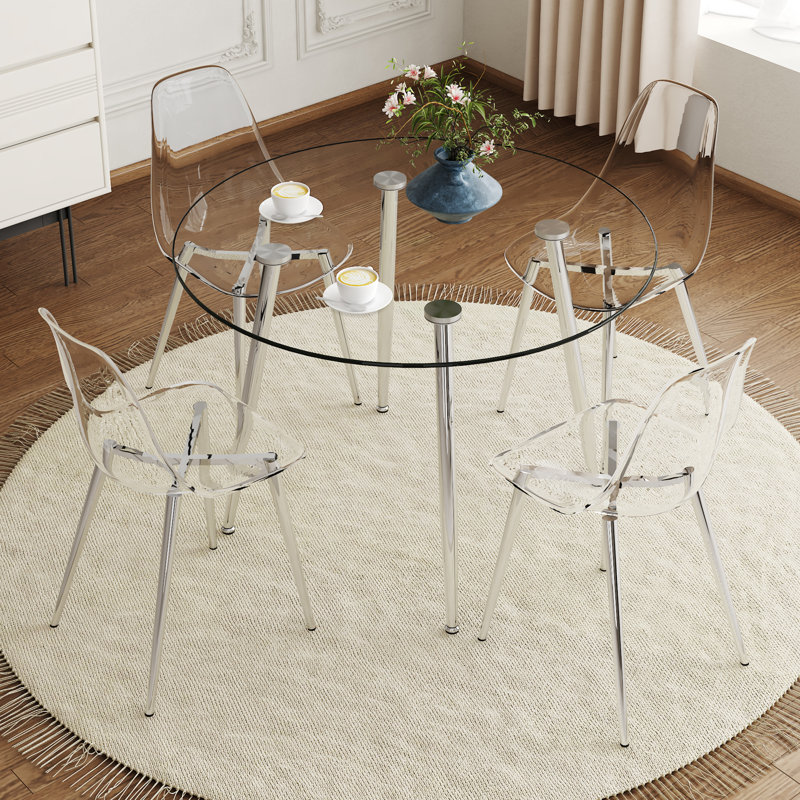 Ivy Bronx Sleek 5 piece dining set round tempered glass table silver metal legs 4 transparent pet chairs modern minimalist Wayfair